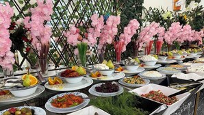 Uma mesa de buffet com diversos pratos, incluindo saladas, frutas e frutos do mar.