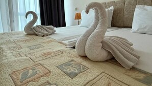 Quarto de hotel com uma cama, arranjo de toalha em formato de cisne, tapete estampado e janela com cortinas.