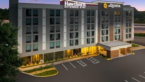Um hotel com vários andares, ostentando as marcas 'Hawthorn Extended Stay' e 'La Quinta', com design moderno, grandes janelas e estacionamento.