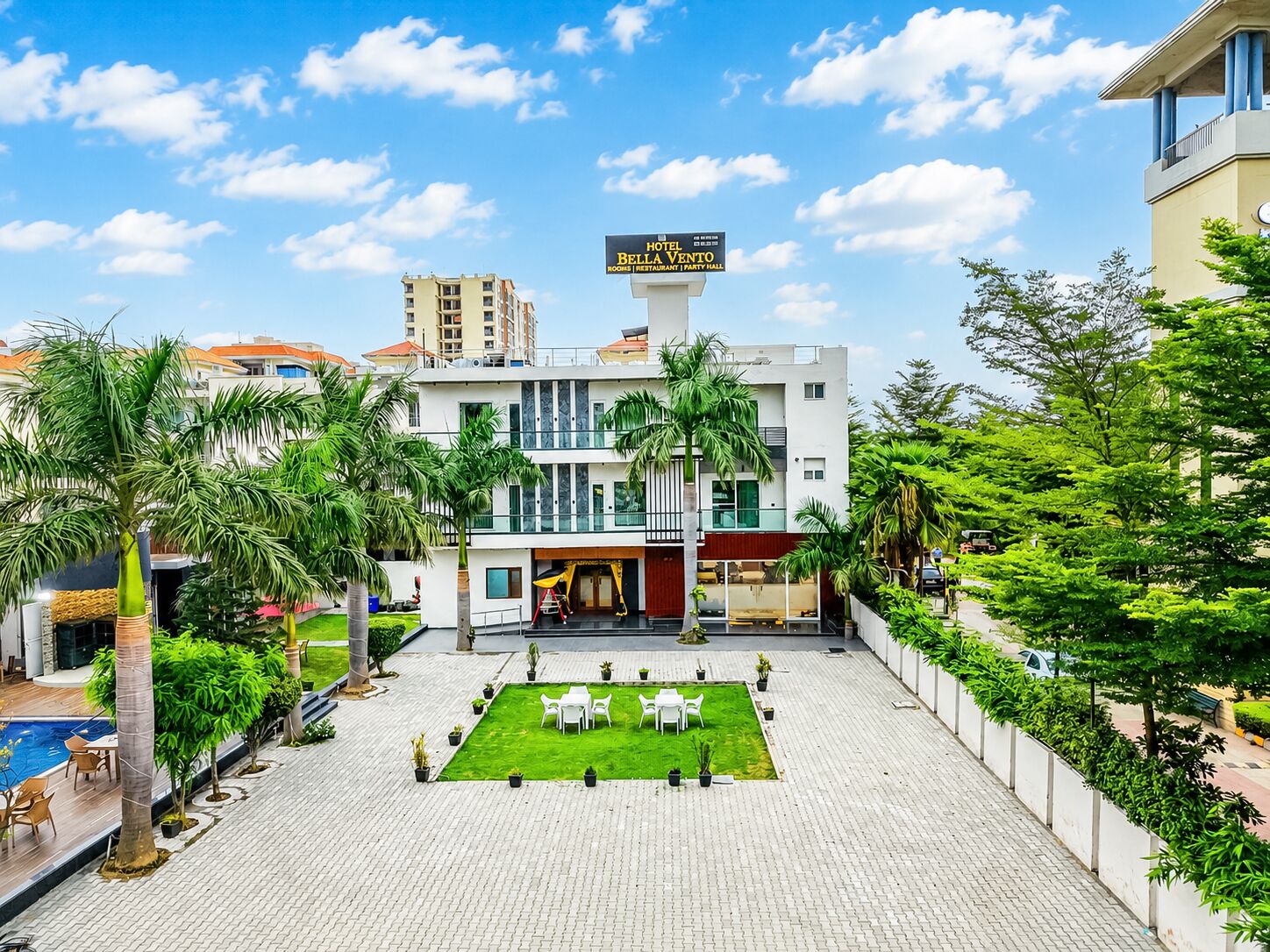 Um hotel com um jardim no terraço, área de estar ao ar livre e uma placa indicando que é restaurante e salão de festas.