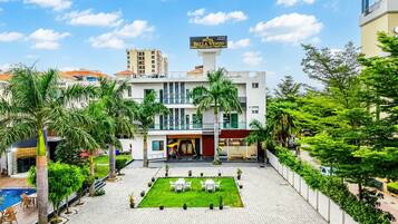 Um hotel com um jardim no terraço, área de estar ao ar livre e uma placa indicando que é restaurante e salão de festas.