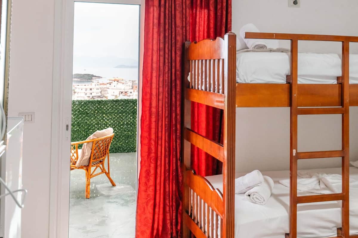 Quarto com beliche de madeira, porta de correr de vidro que dá para uma varanda e ar condicionado na parede.