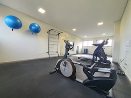 Uma academia com equipamentos de exercício, uma barra de puxada e duas bolas de ginástica grandes.