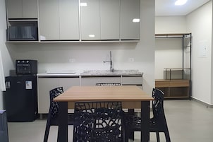 Uma cozinha compacta com mesa e cadeiras, geladeira e pia.