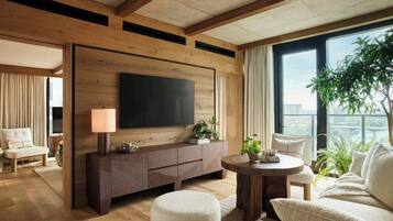 Uma sala de estar moderna com uma grande TV de tela plana, painéis de madeira, uma mesa de centro redonda e vista para um horizonte urbano através de amplas janelas.