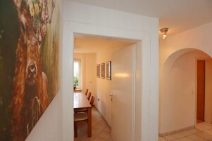 Um corredor com área de refeições, uma porta para outro quarto e uma parede com uma moldura.