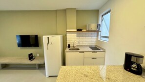 Uma cozinha compacta com geladeira, micro-ondas, pia e cafeteira.