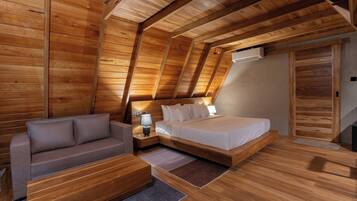 Um interior em madeira com uma cama, um sofá e uma mesa de cabeceira.