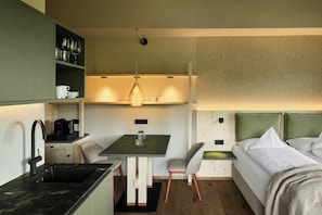 Quarto compacto com cozinha compacta, área de jantar e cama.