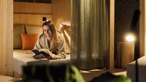 Um quarto acolhedor com cama, um espaço para leitura e uma janela com cortina.