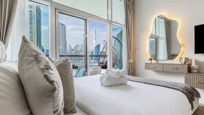 Quarto de hotel moderno com uma cama grande, vista para a cidade, um espelho redondo e televisão montada na parede.