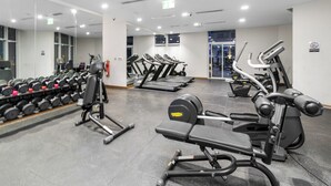 Uma academia equipada com esteiras, halteres e máquinas de musculação.