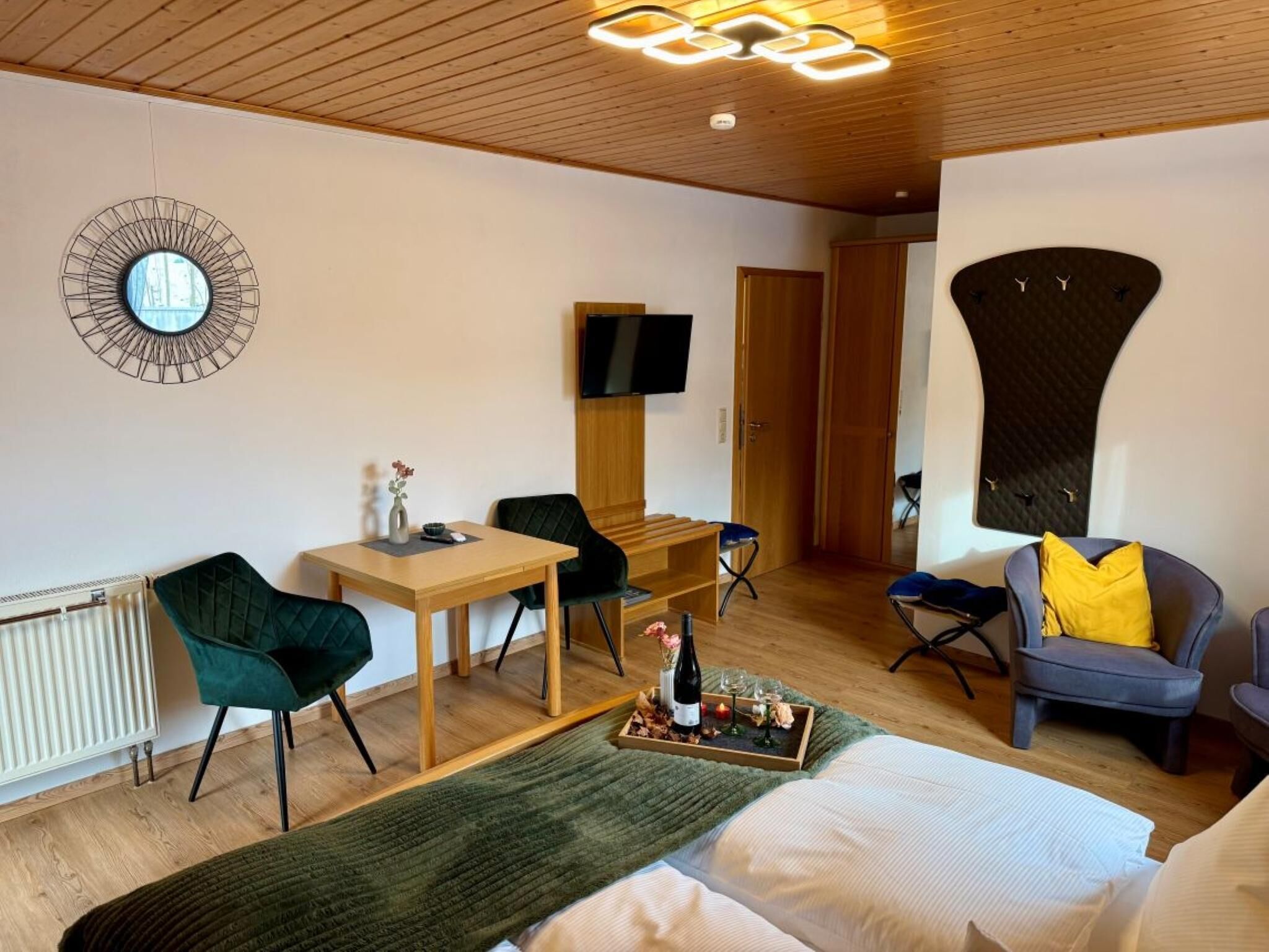 Quarto de hotel moderno com cama, escrivaninha, duas cadeiras, TV e uma obra de arte única na parede.