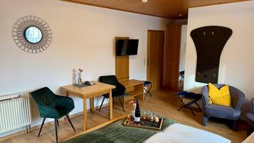 Quarto de hotel moderno com cama, escrivaninha, duas cadeiras, TV e uma obra de arte única na parede.