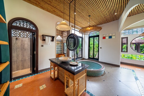 Casa de banho com um espelho grande, uma pia e uma banheira redonda.