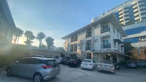 Um edifício de vários andares com uma placa que diz 'Kangaroo'. Vários carros estão estacionados na frente.