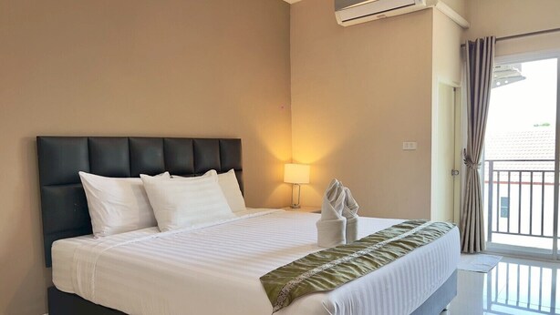 Quarto de hotel com cama, luminária, aparelho de ar condicionado e vista para o exterior.