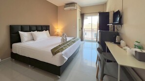 Quarto de hotel com cama, escrivaninha, cadeira, televisão e aparelho de ar condicionado.