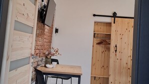 Quarto com teto de madeira, claraboia, parede de tijolos, porta de madeira e piso estampado.