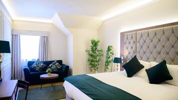 Quarto de hotel com cama, sofá, uma mesinha e uma cadeira.