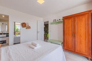 Quarto com cama, guarda-roupa, espelho e vista para o exterior.