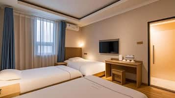 Quarto de hotel com duas camas, uma mesa, uma televisão e um aparelho de ar condicionado.
