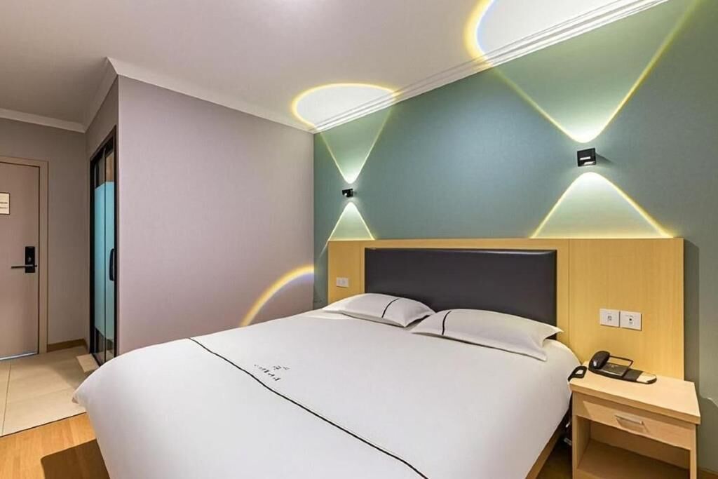 Quarto de hotel moderno com uma cama grande, mesas de cabeceira e iluminação embutida na parede.