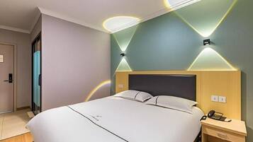 Quarto de hotel moderno com uma cama grande, mesas de cabeceira e iluminação embutida na parede.