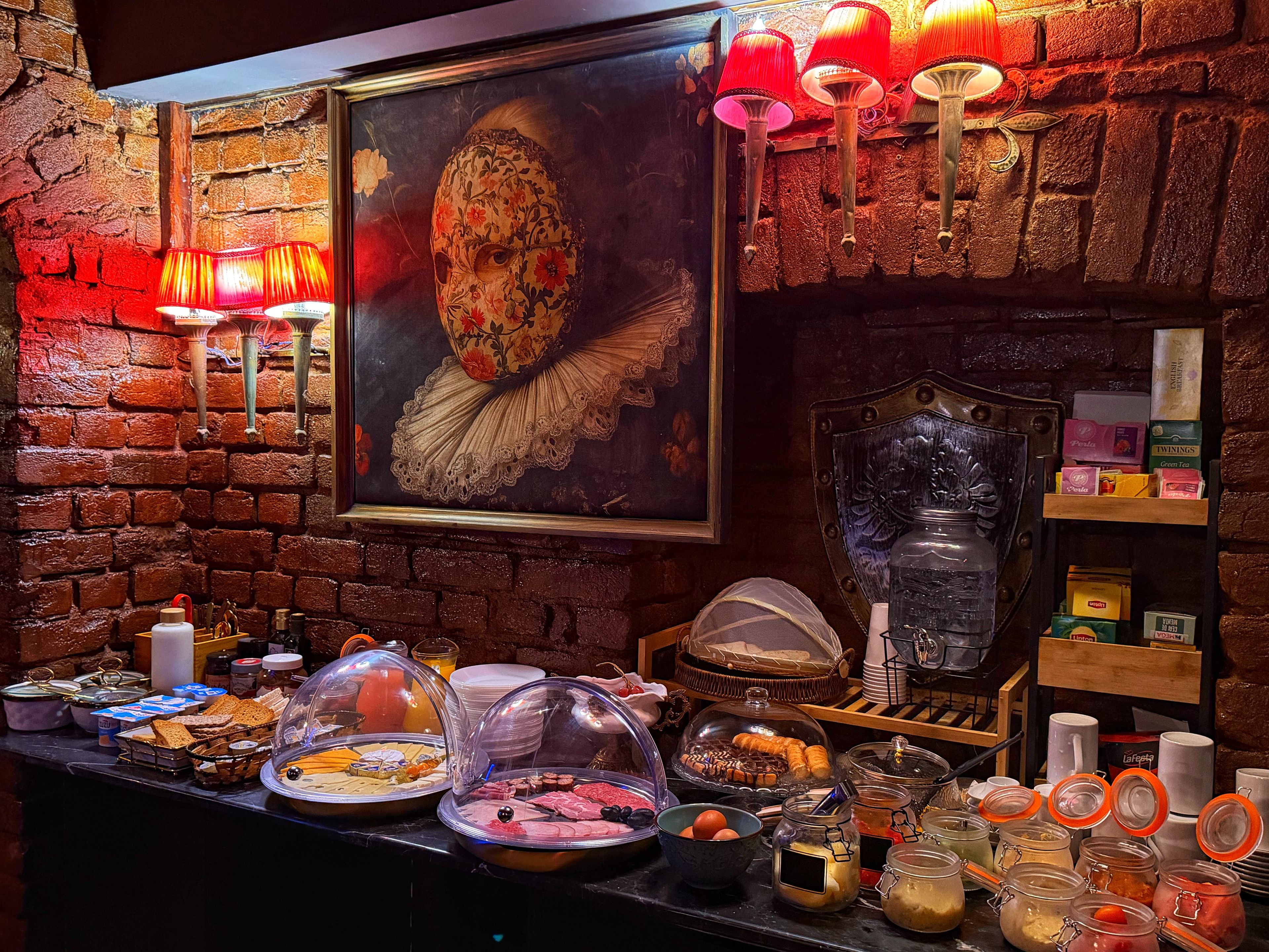 Um buffet de café da manhã com diversos alimentos e uma grande pintura floral na parede.
