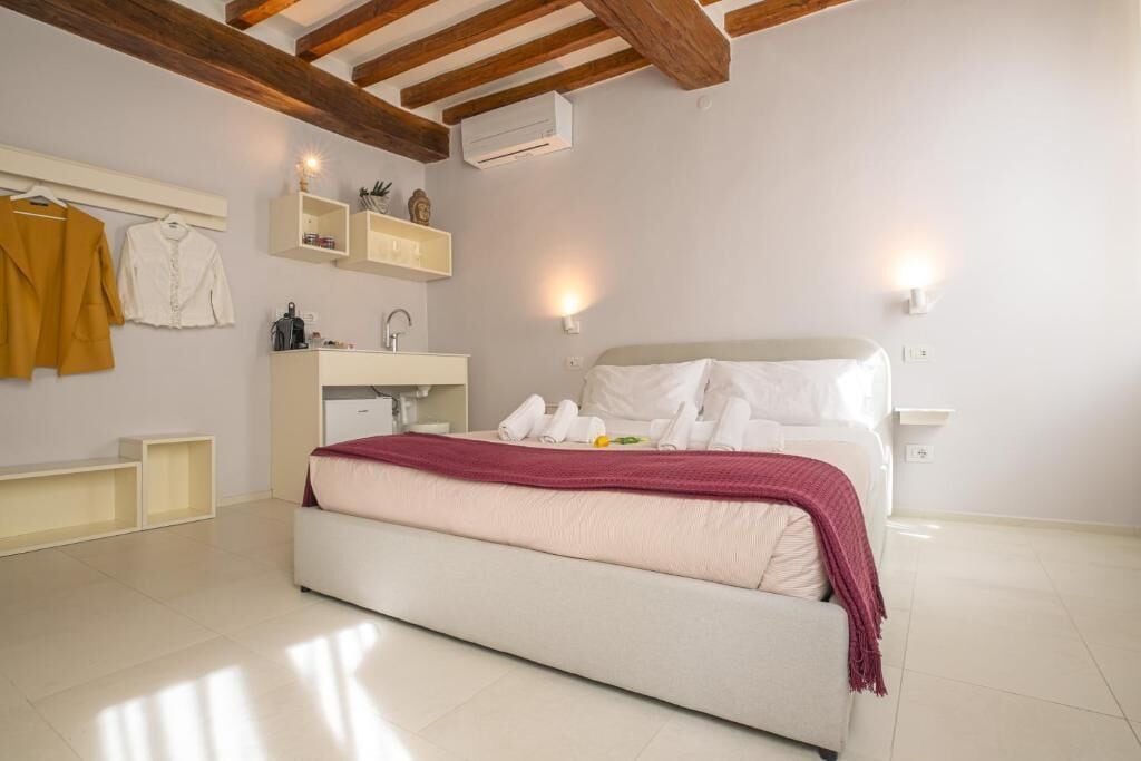Quarto com cama, mesas de cabeceira, guarda-roupa e prateleira na parede com toalhas.