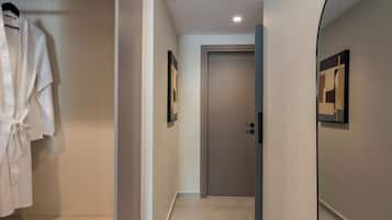 Um corredor com um roupão pendurado à esquerda, uma porta no final e quadros nas paredes.