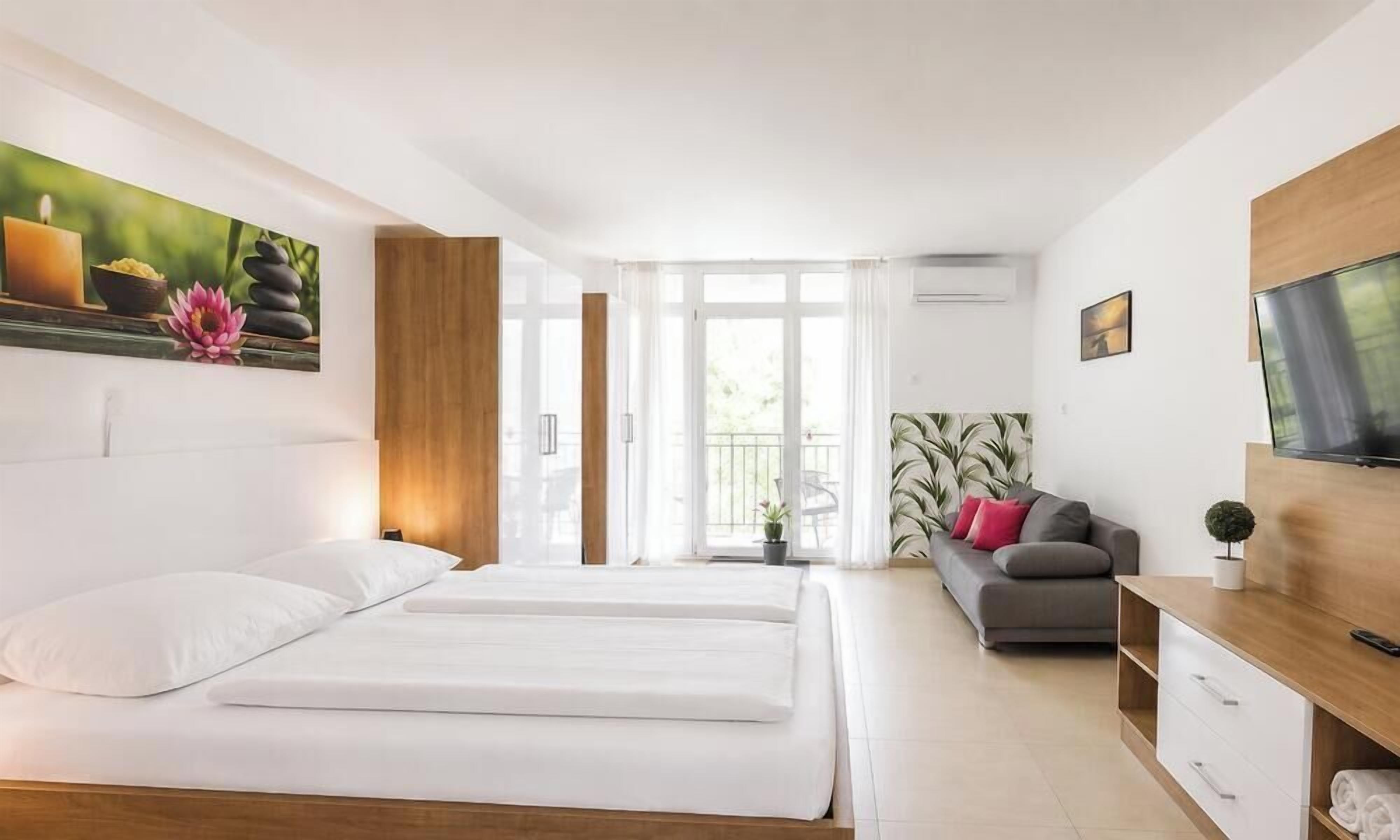 Um quarto moderno com uma cama, um sofá, uma televisão e um quadro na parede.