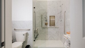 Uma casa de banho com sanita, chuveiro e lavatório.