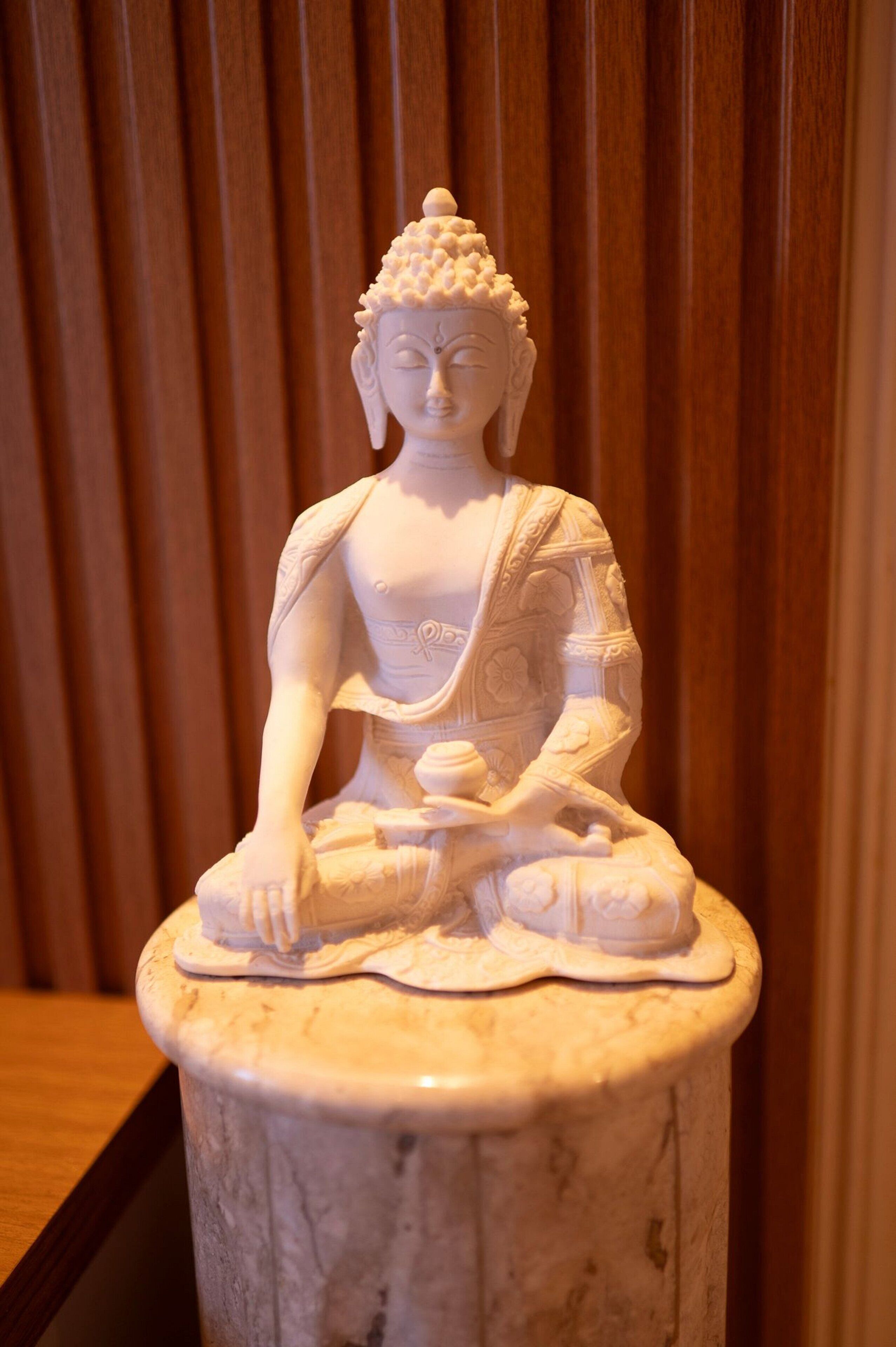 Uma estátua de Buda sentado sobre um pedestal de mármore.