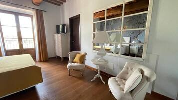 Quarto com cama, duas poltronas, uma mesinha, janela com vista e um armário.