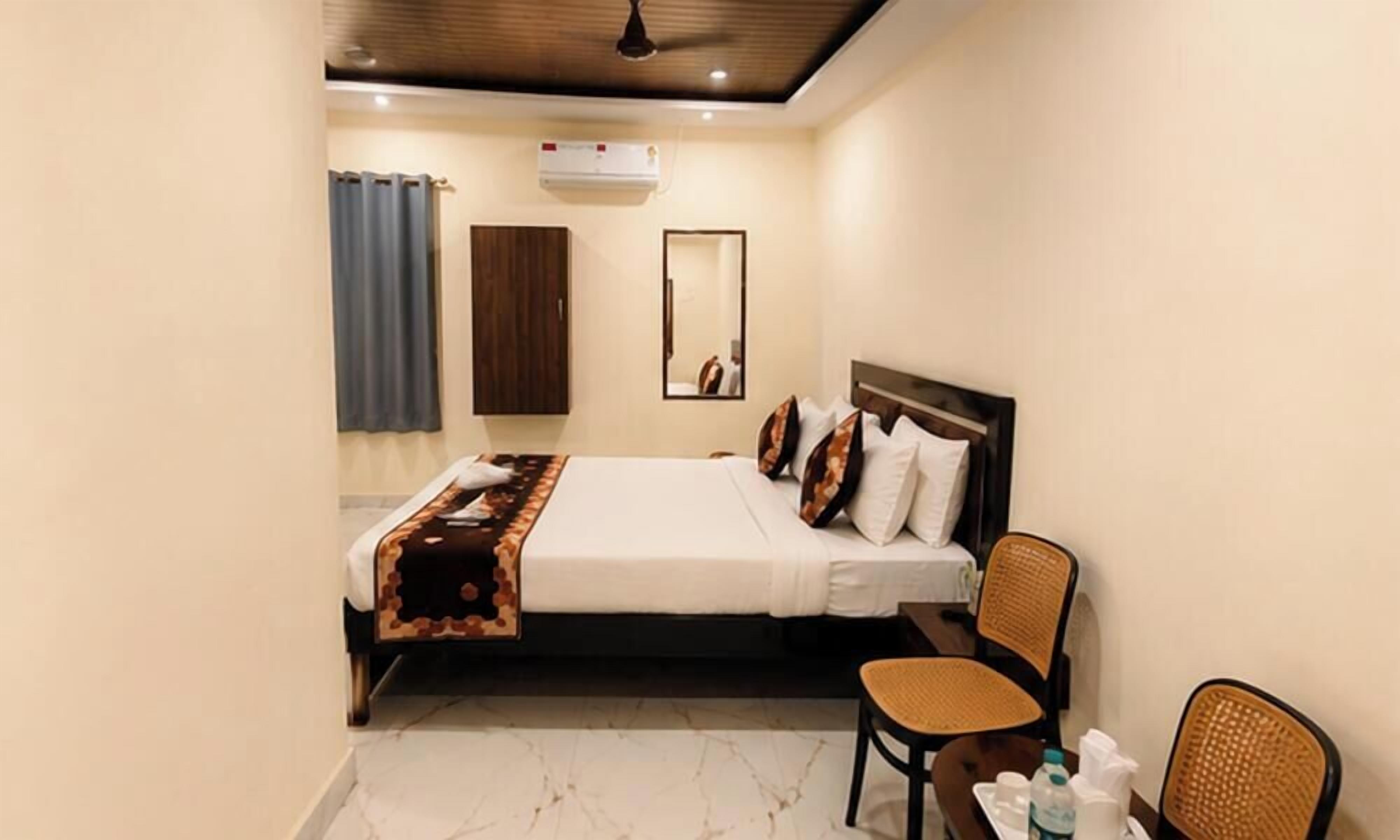 Quarto de hotel com uma cama, uma cadeira, um espelho e um ventilador de teto.