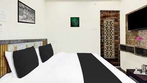 Quarto de hotel com cama, televisão, porta decorativa e quadro na parede.
