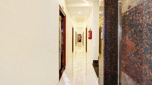 Um corredor de hotel com piso lustroso, um extintor de incêndio e um alarme de incêndio na parede.