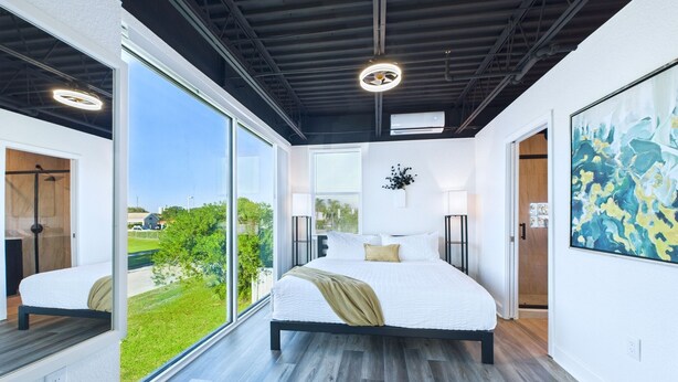 Um quarto moderno com uma cama grande, vista para o exterior e um ventilador de teto.