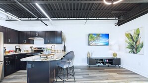 Cozinha moderna com armários escuros, uma ilha central e um espaço de refeições com cadeiras.
