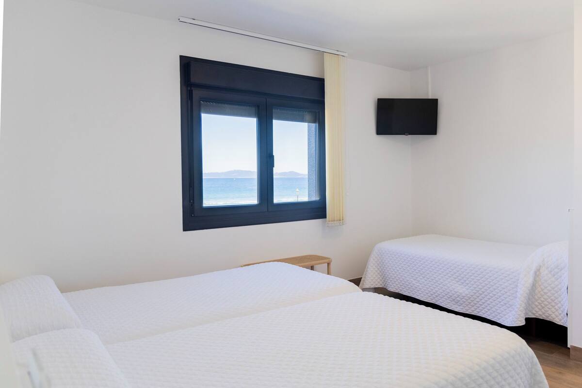 Quarto com duas camas, janela com vista, televisão de tela plana e uma pequena mesa.