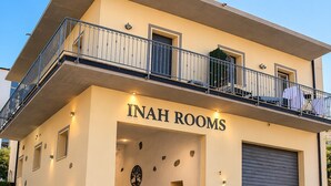Um edifício de dois andares com uma placa na parte inferior que diz 'INAH ROOMS'.