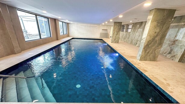 Piscina interior com água cristalina, paredes e chão revestidos em azulejo.