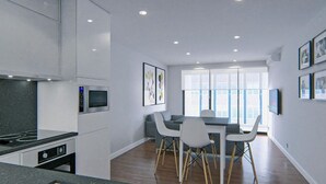 Cozinha moderna com área de refeições, com forno embutido, micro-ondas e mesa de jantar com cadeiras.