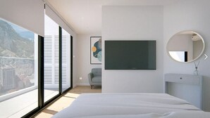 Quarto moderno com cama, janela ampla, TV na parede e espelho redondo.