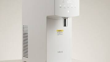 Um dispensador de água moderno, branco e fixo, com visor digital, sobre uma superfície de mármore.
