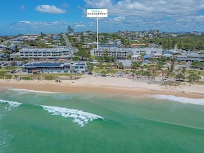 Uma vila costeira com praia, edifícios e uma placa a indicar 'Holiday Management Co.'