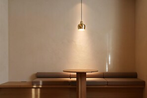 Quarto minimalista com uma mesa redonda de madeira e um banco.
