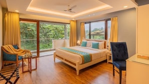 Quarto com cama, cadeira, escrivaninha e vista para o verde.
