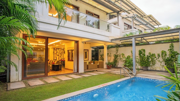 Uma casa moderna com piscina, varanda coberta e jardim bem cuidado.